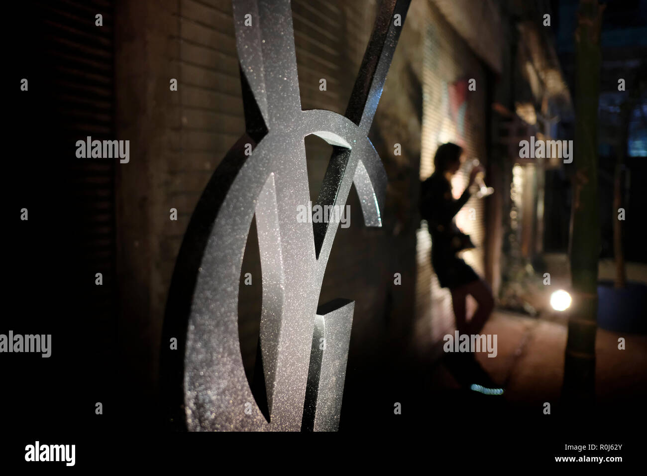 View of a young woman having a drink across Yves Saint Laurent logo ...