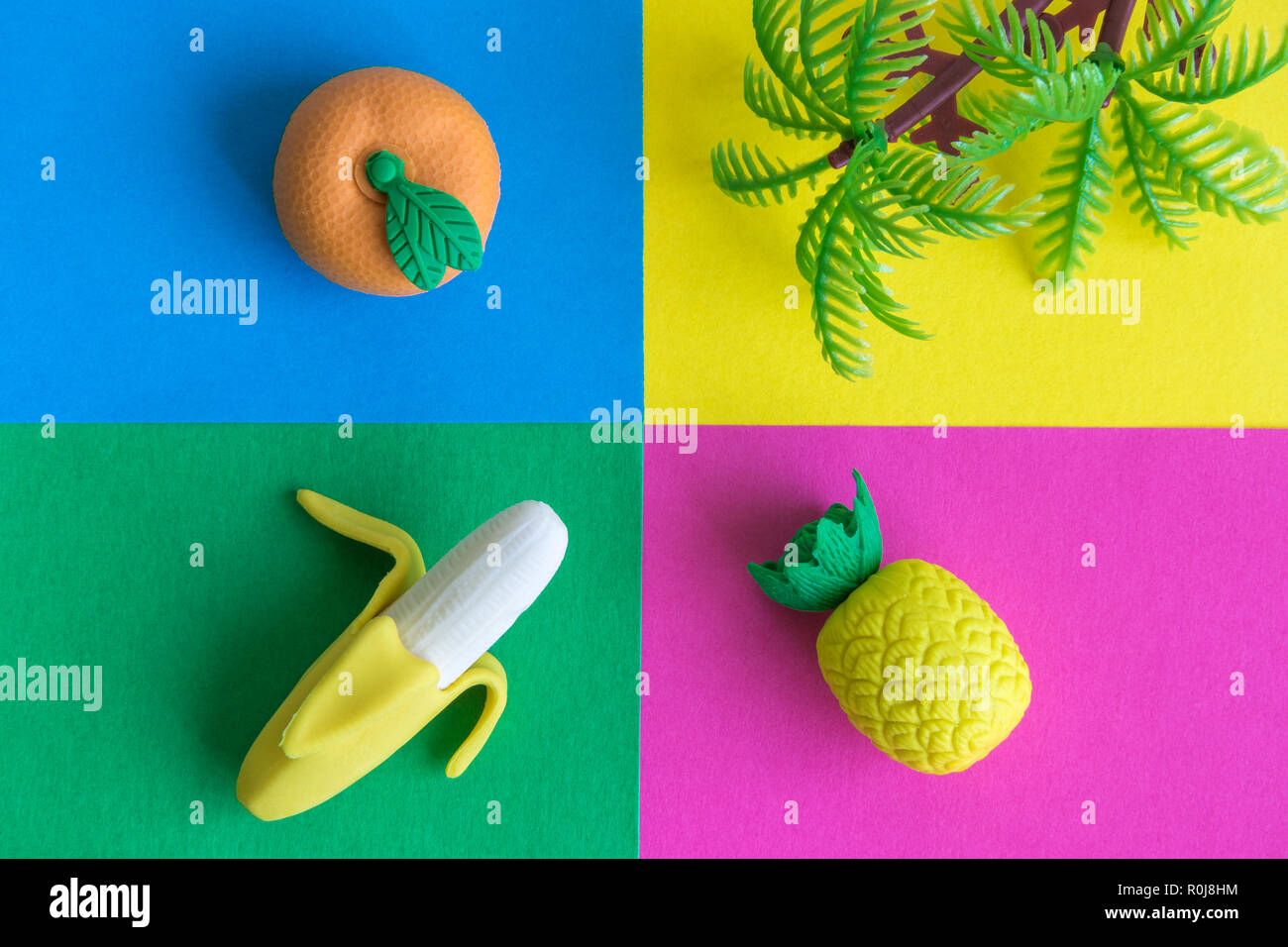 Tropical rubber fruits and plastic palm tree on colorful background ...