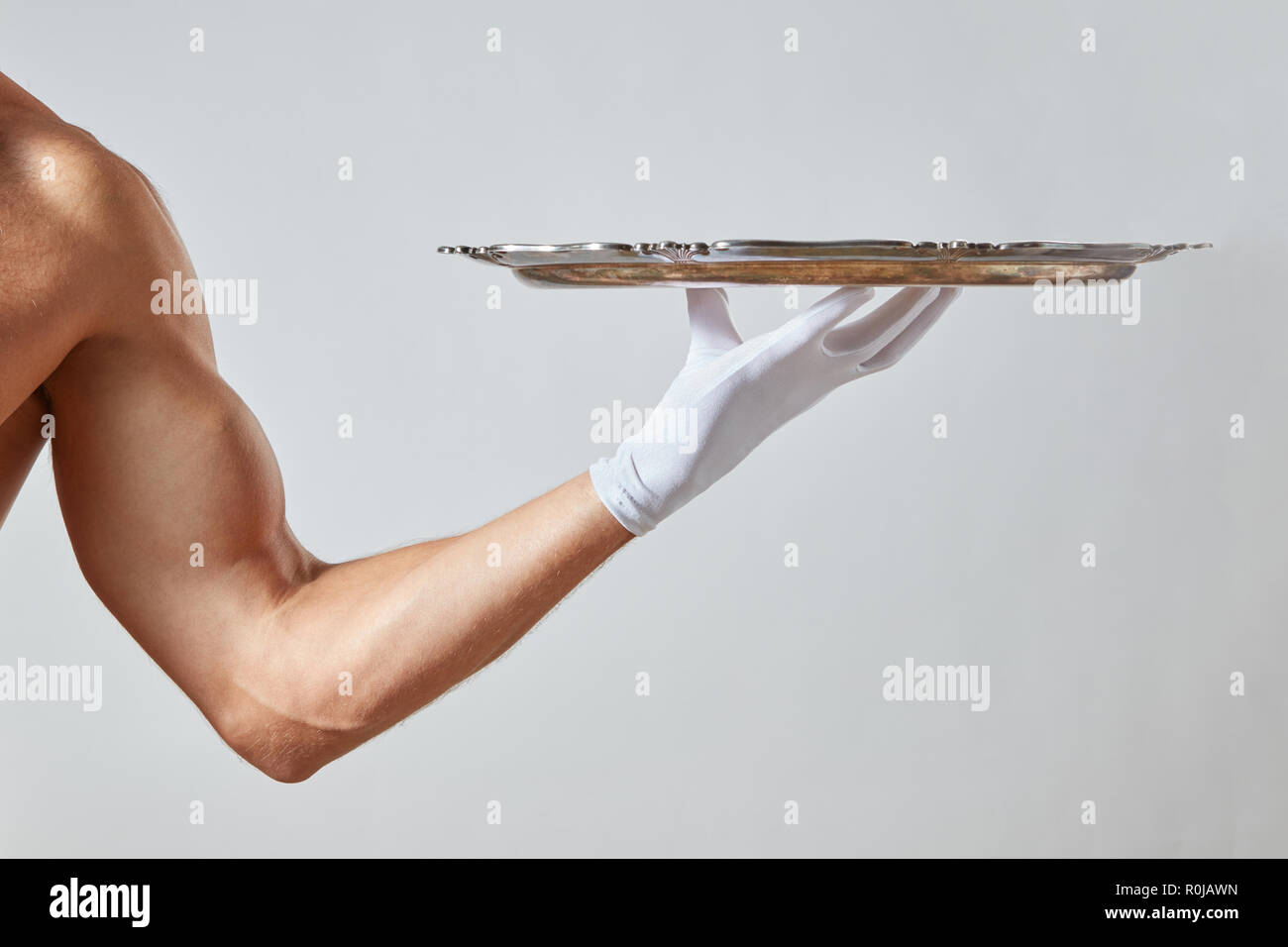 Muscular hand of waiter in a white glove holding a silver vintage empty ...
