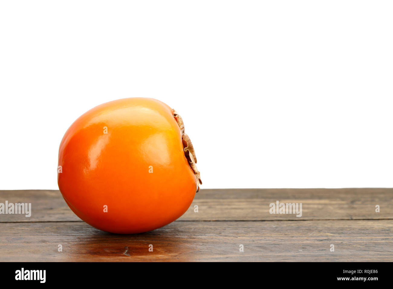 one persimmon on a table on a white wall background. place for text ...