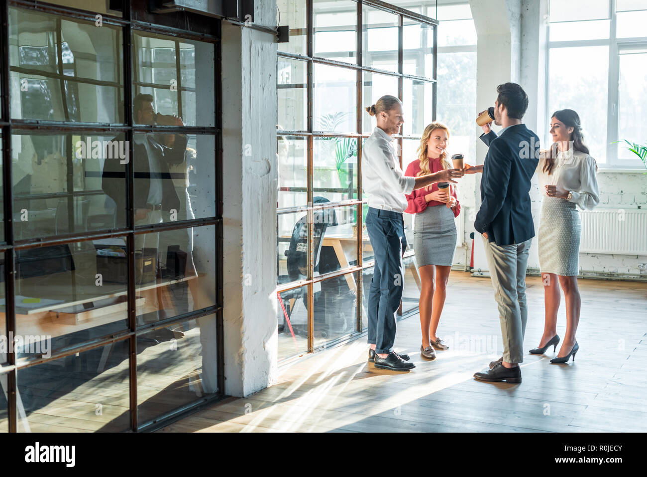 business colleagues having conversation in hall during coffee break ...