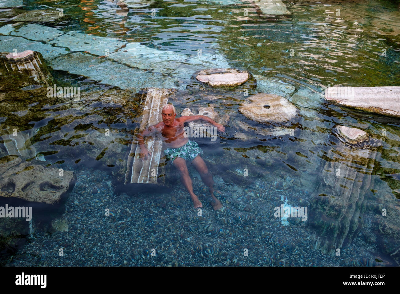 Man relaxing in the sacred pool of Cleopatra at the ruins of the ...
