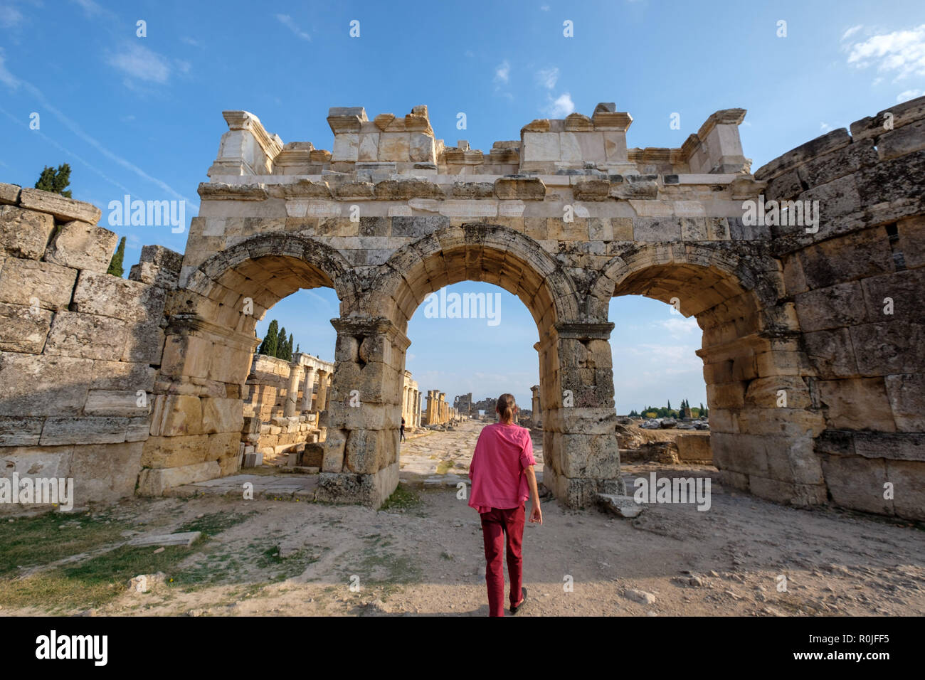 Rear view of a man walking to the ruins of the Frontinus Gate at the ...