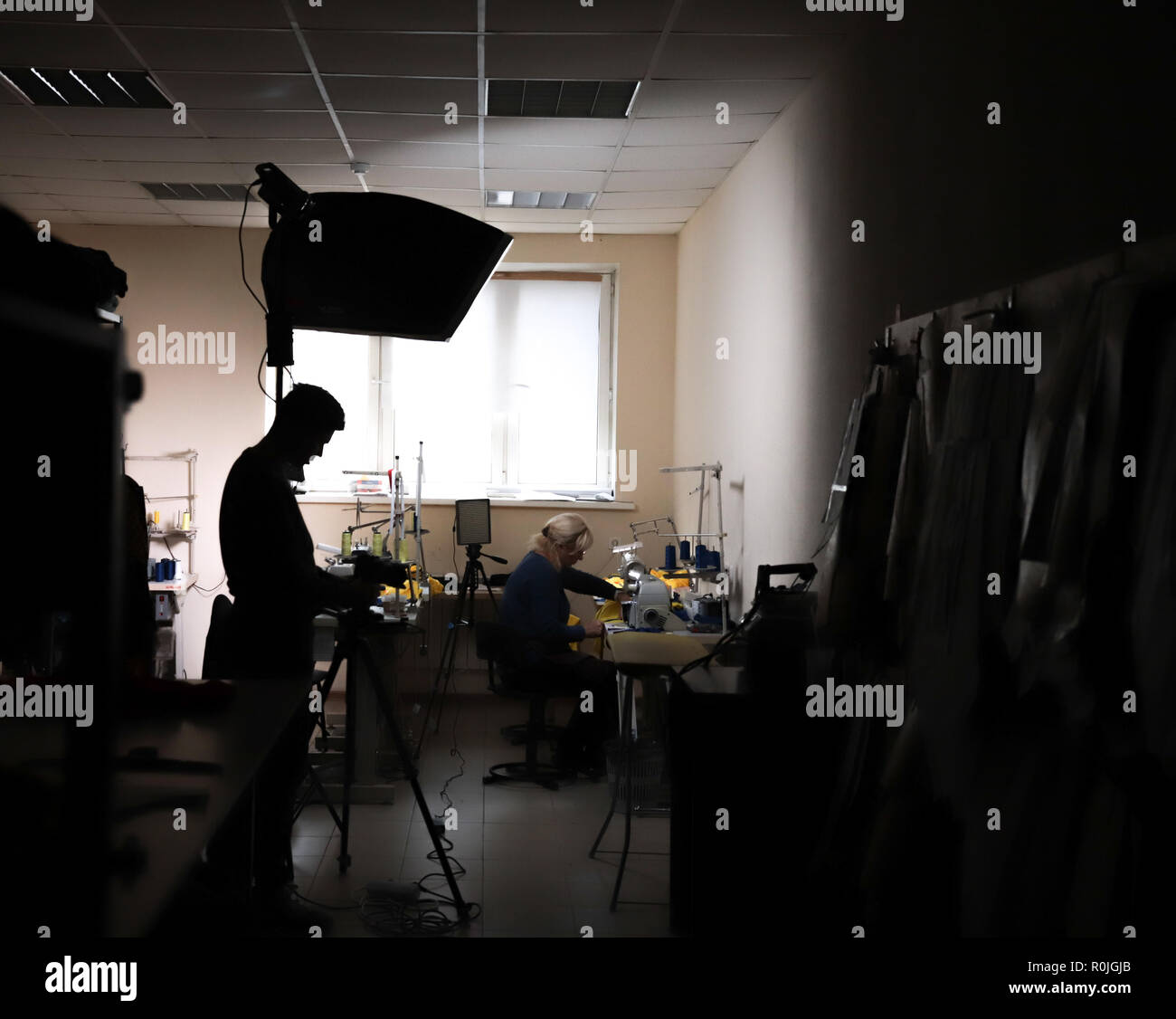 Backstage of clothing factory filming. Operator silhouette. Mid shot ...