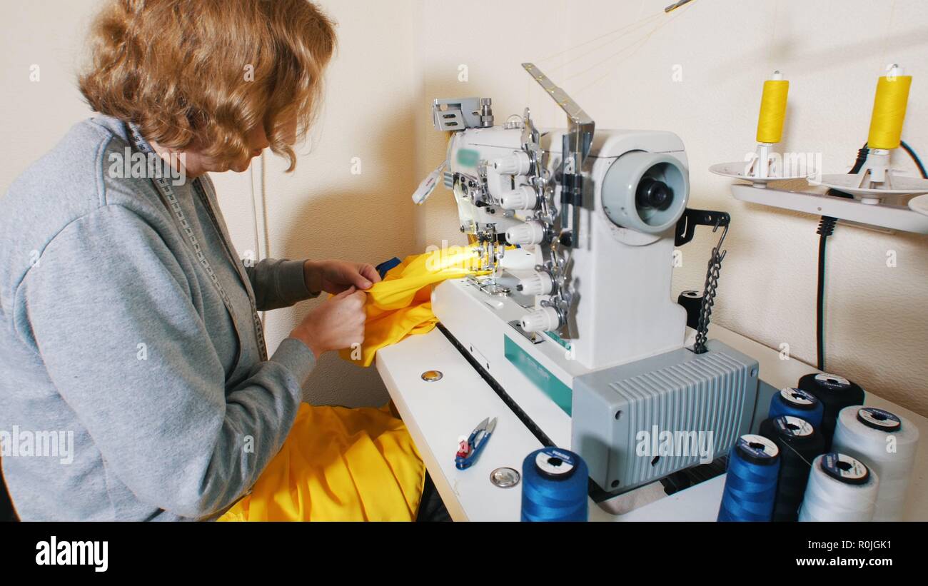 Female tailor working with sewing machine on factory. Mid shot Stock ...