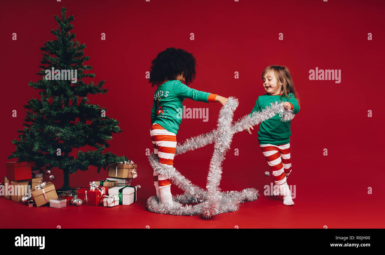 Kids playing with decorative ribbon near a christmas tree. Multi ethnic ...