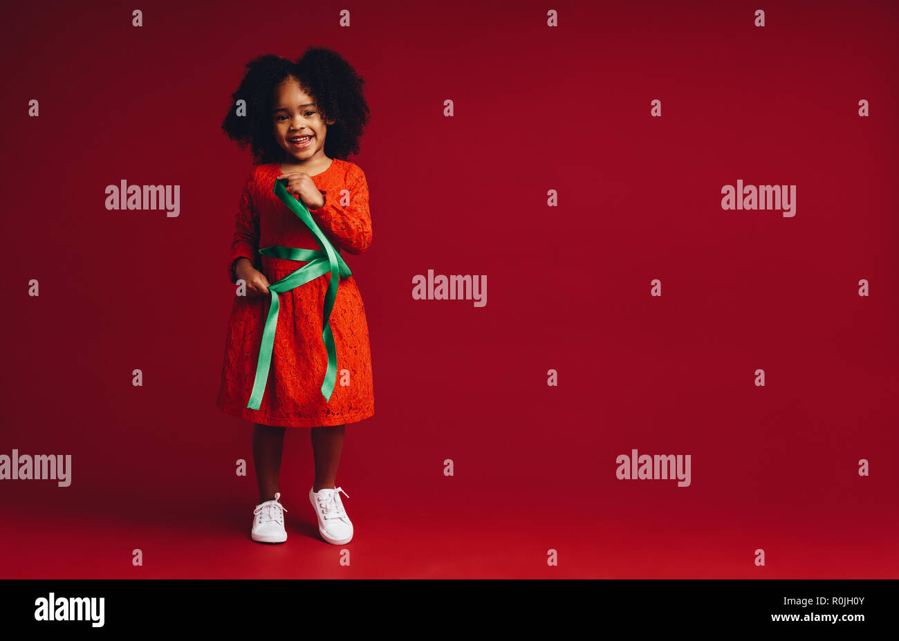 Afro american kid playing with a decorative ribbon. Little girl ...