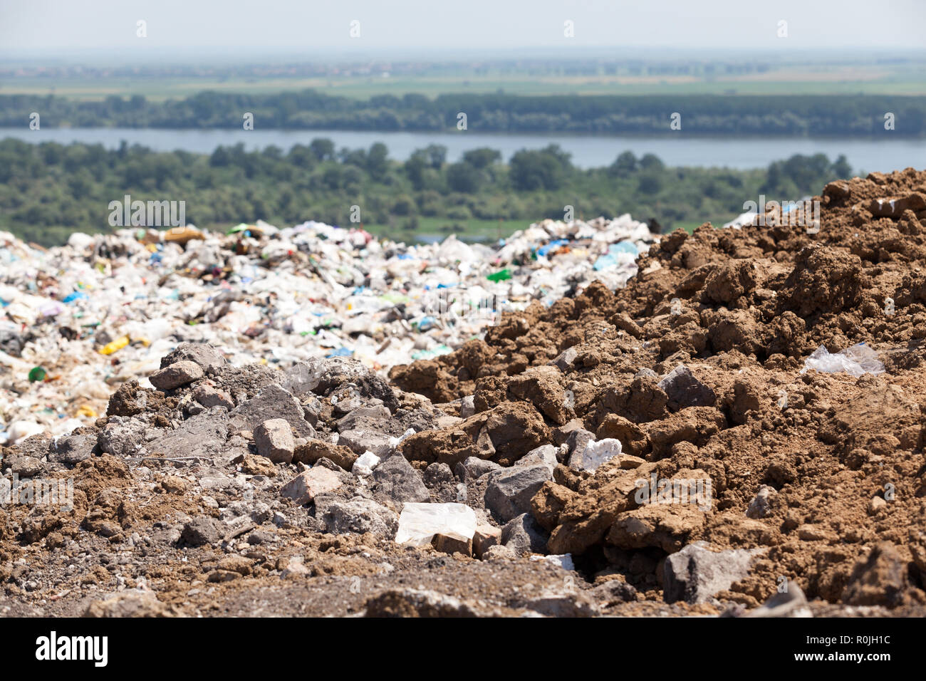 A landfill in the nature. A pile of garbage close to the river bank ...