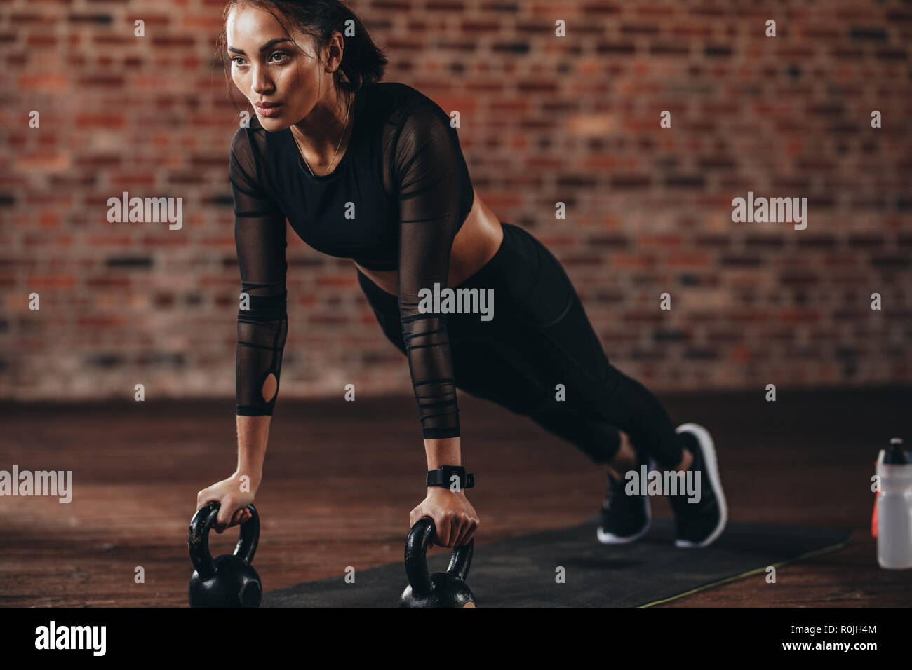 Strong woman doing push-ups on kettle bell in gym. Muscular female ...