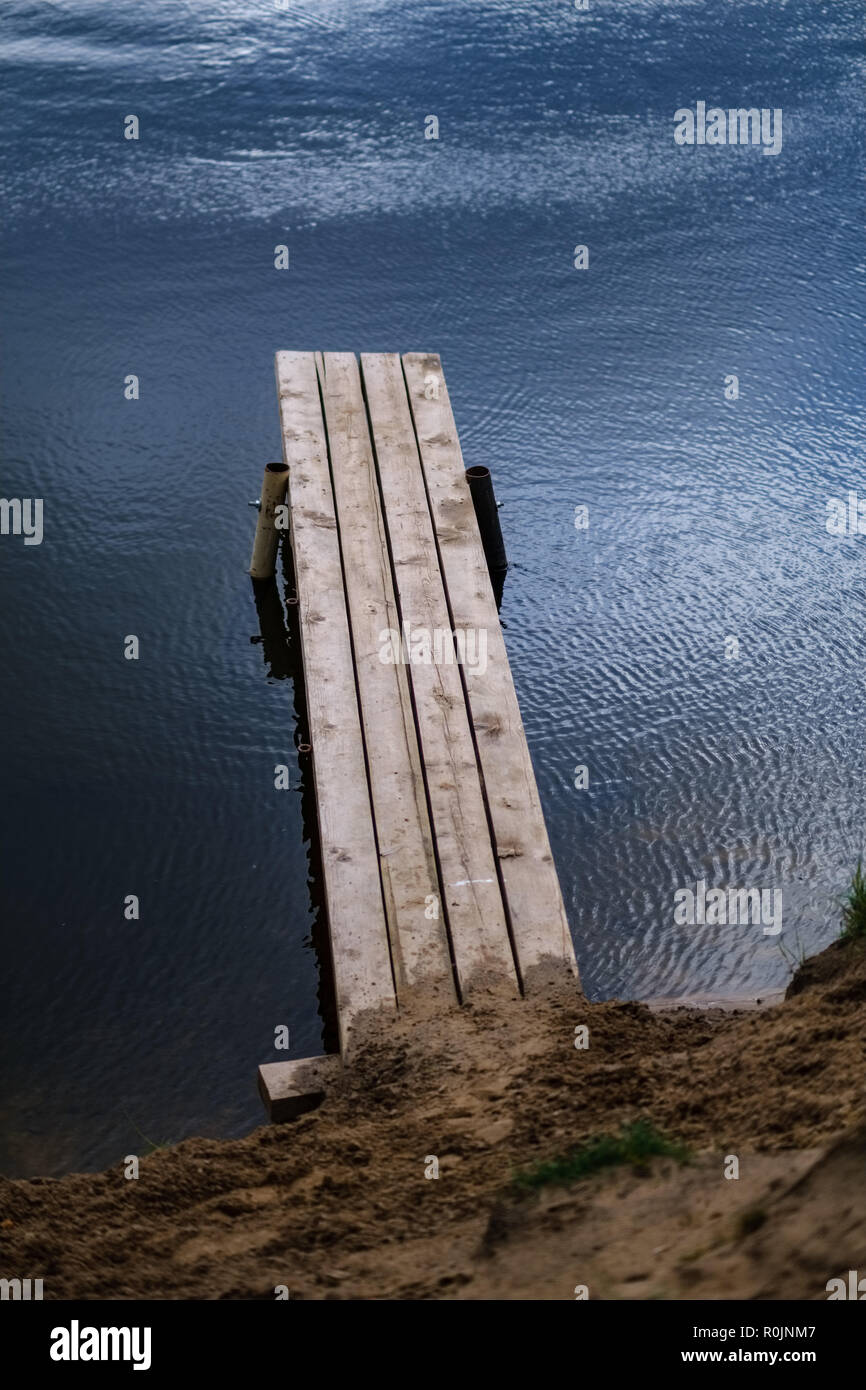 wooden plank bridge over water in forest in autumn with grey colors ...