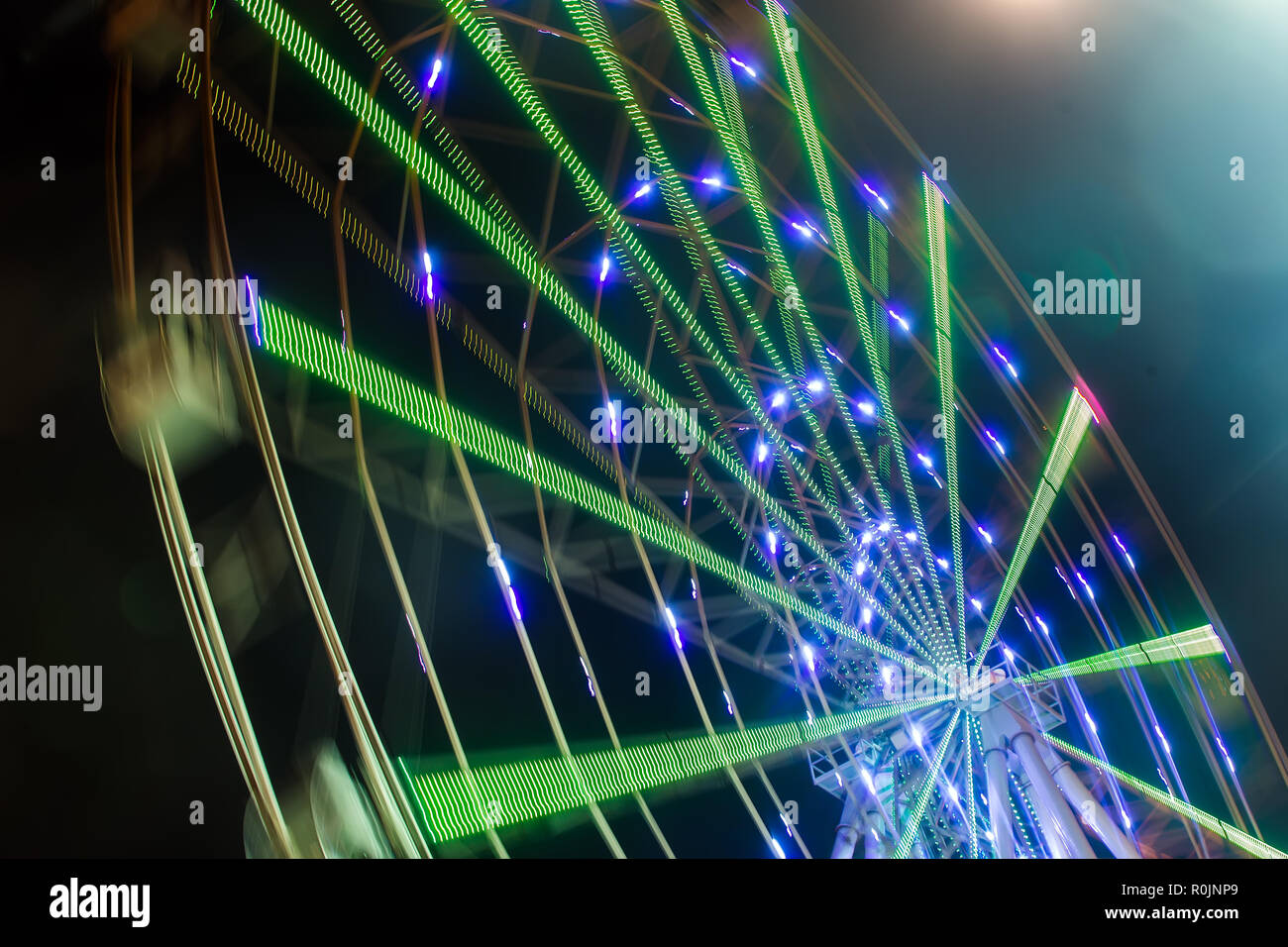 Carnival ride showing a spinning ferris wheel in action- long exposure ...