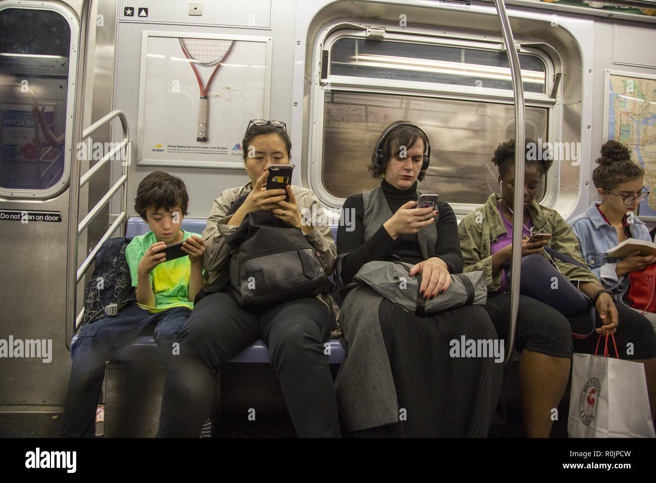 Subway riders on their phones; reading, texting, watching, as they pass ...