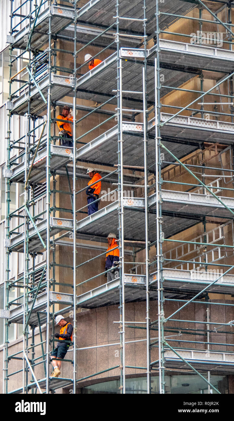 Construction workers on different levels of scaffolding on a building ...