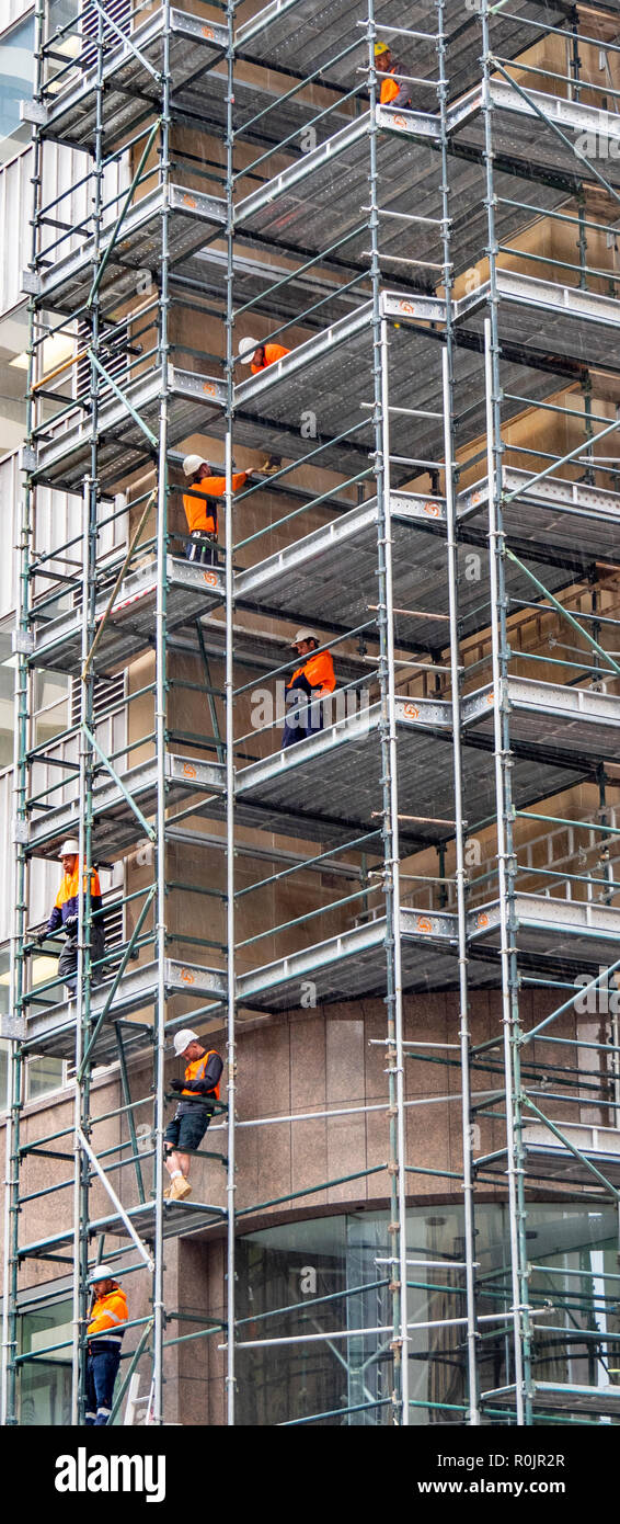 Construction workers on different levels of scaffolding on a building ...