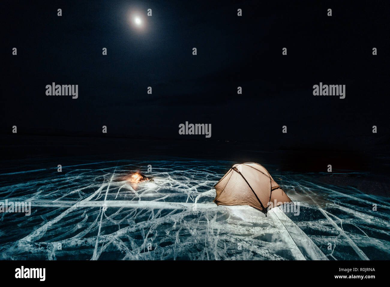 Fire on ice at night. Campground on ice. Tent stands next to bonfire ...