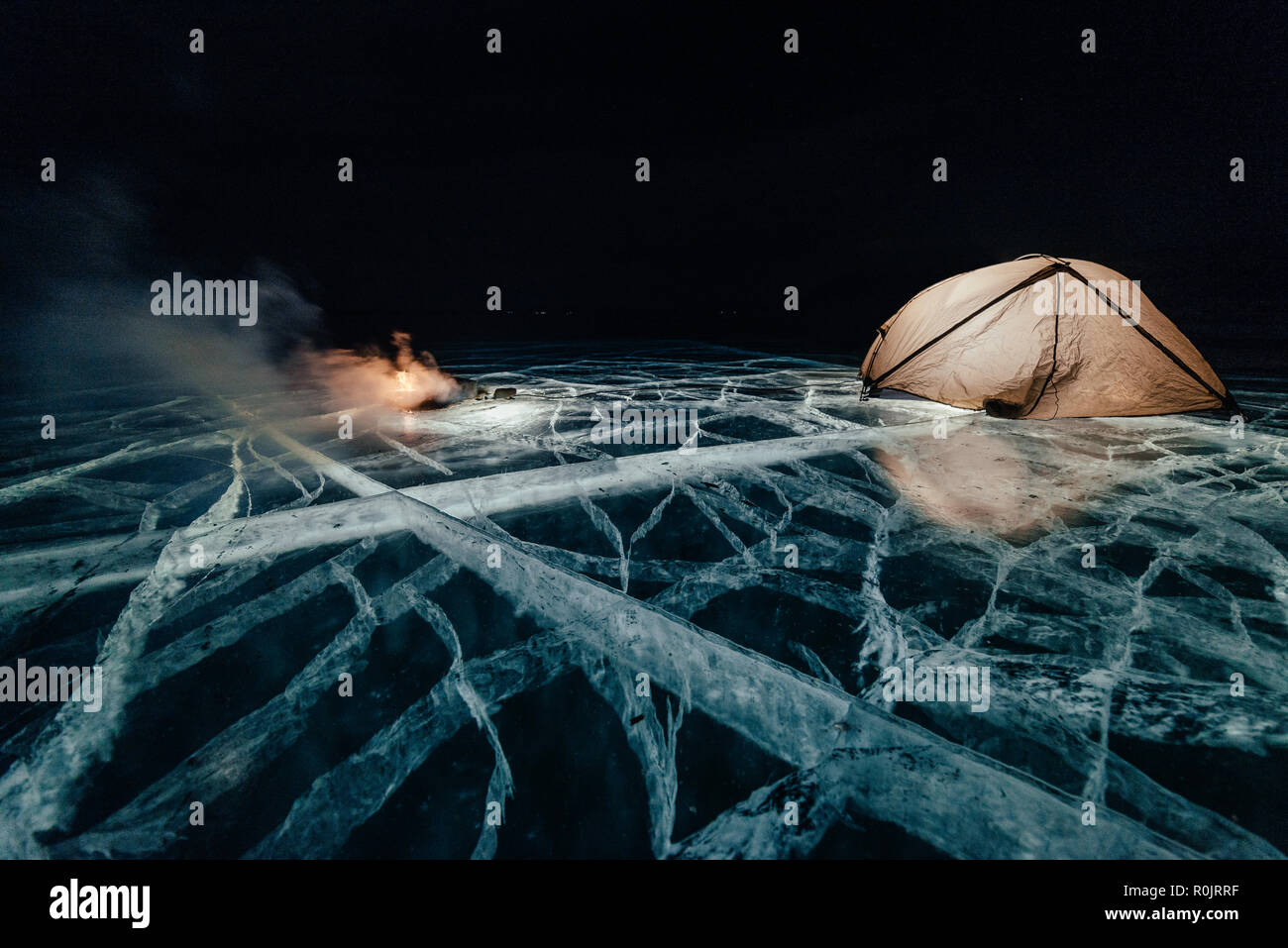 Fire on ice at night. Campground on ice. Tent stands next to bonfire ...