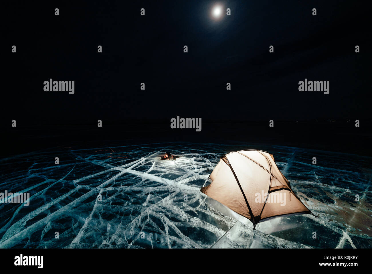 Fire on ice at night. Campground on ice. Tent stands next to bonfire ...