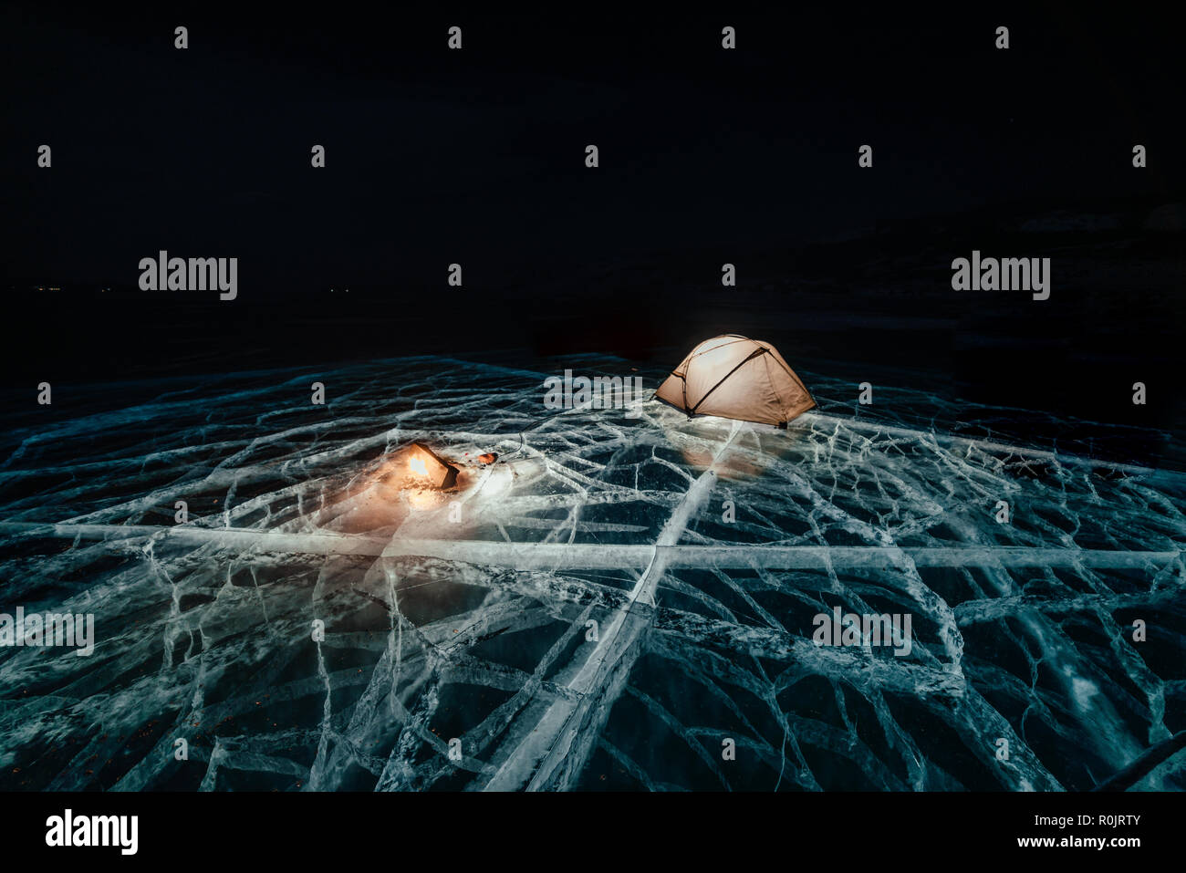 Fire on ice at night. Campground on ice. Tent stands next to bonfire ...