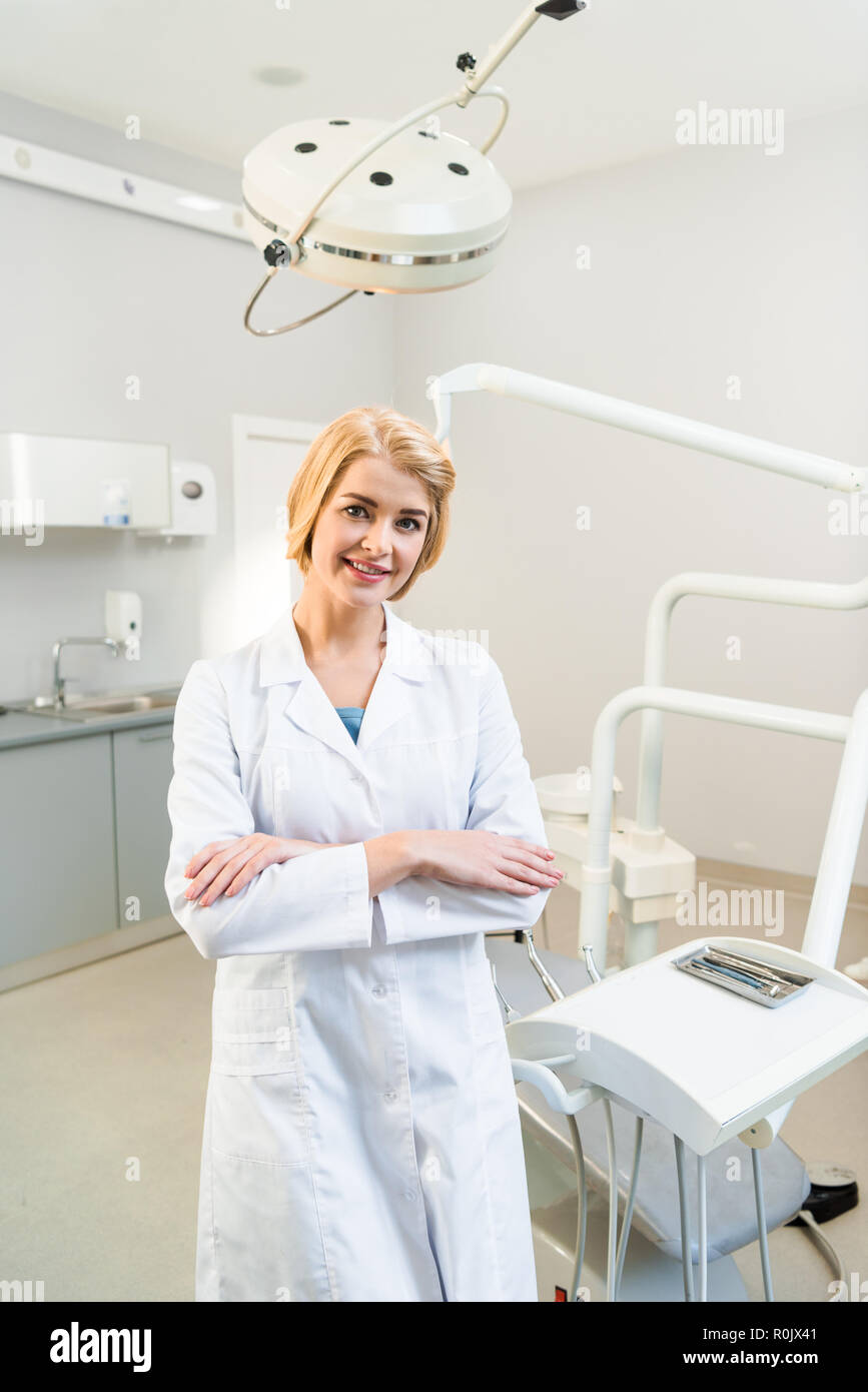 beautiful young dentist with crossed arms looking at camera in office ...