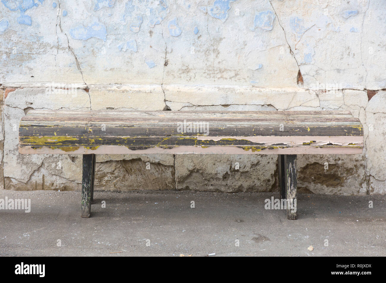 Weathered old aged wooden bench. Destroyed grunge blue plaster wall ...