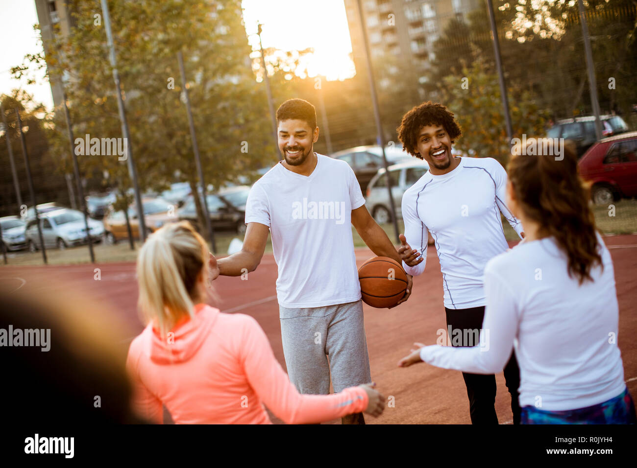 Group of multiethnic young people playing basketball on court Stock ...