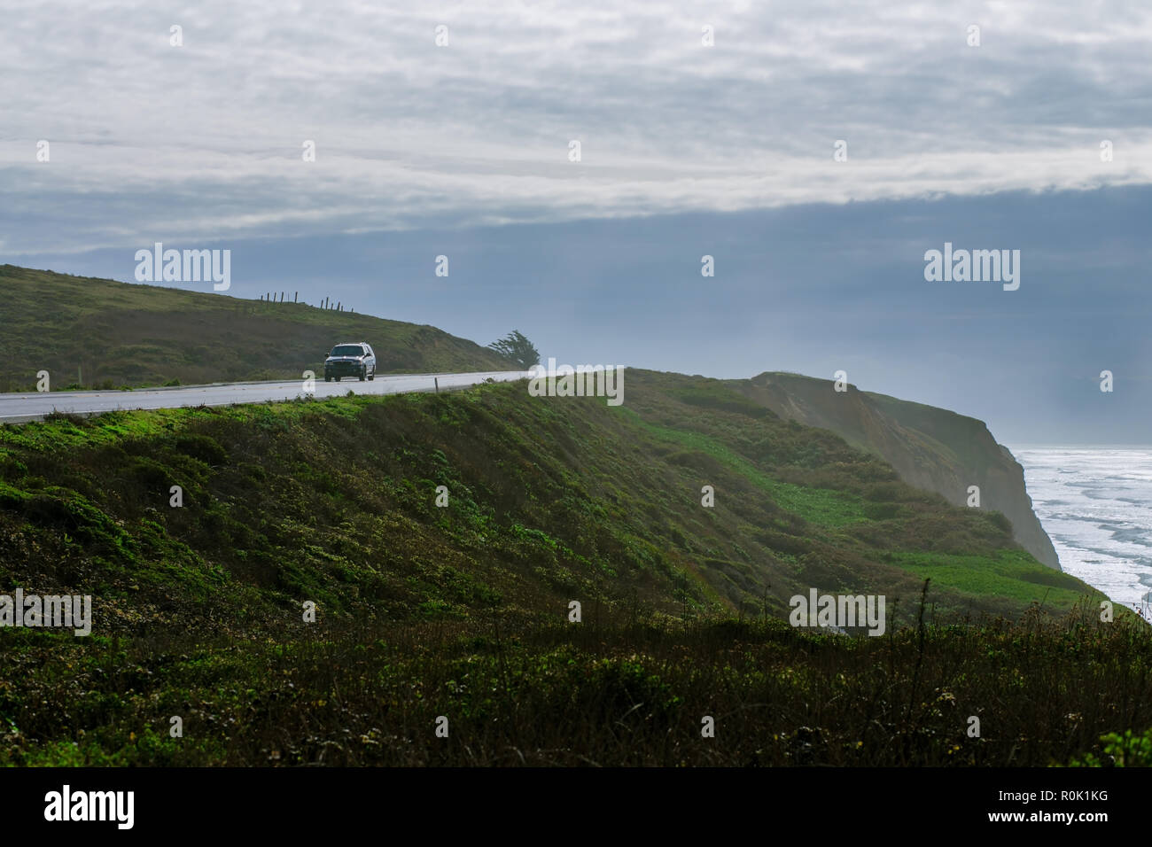 Car driving down scenic highway 1, on a steep cliff overlooking the ...