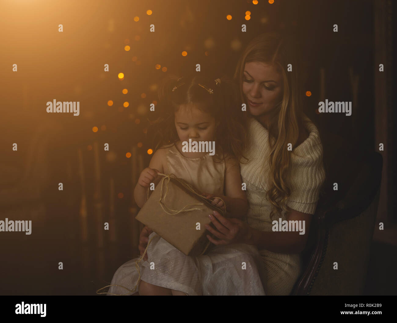 The girl is sitting on his mother's lap with a Christmas present ...