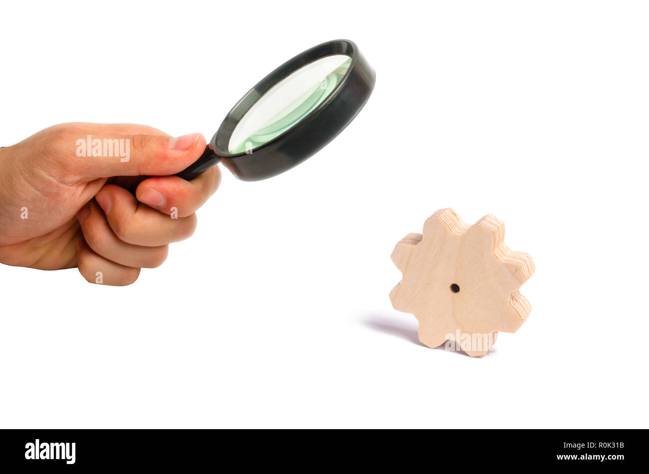 Magnifying glass is looking at the Wooden gear on a white background ...