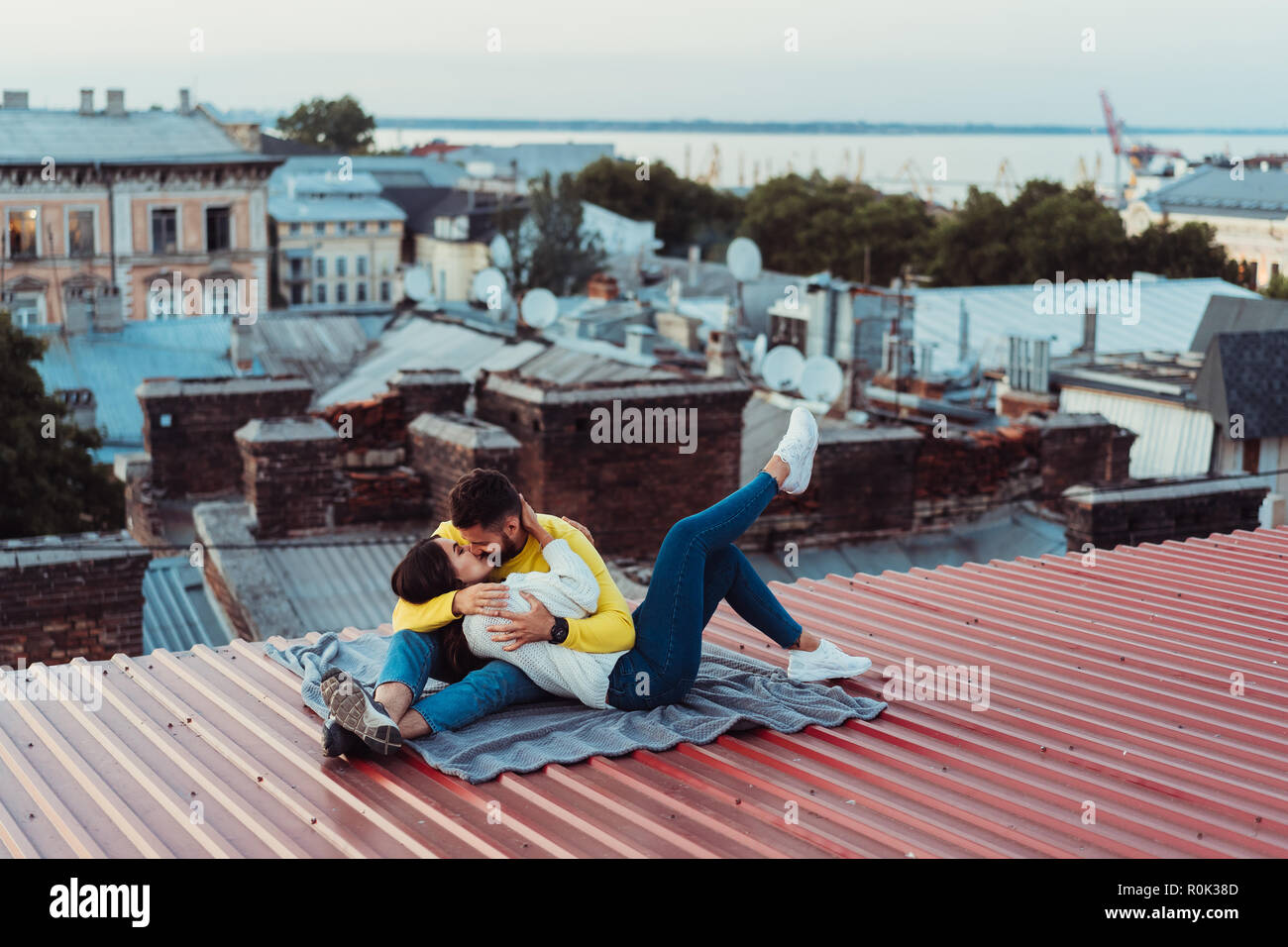 Loving young couple is sitting on the roof of the house Stock Photo - Alamy