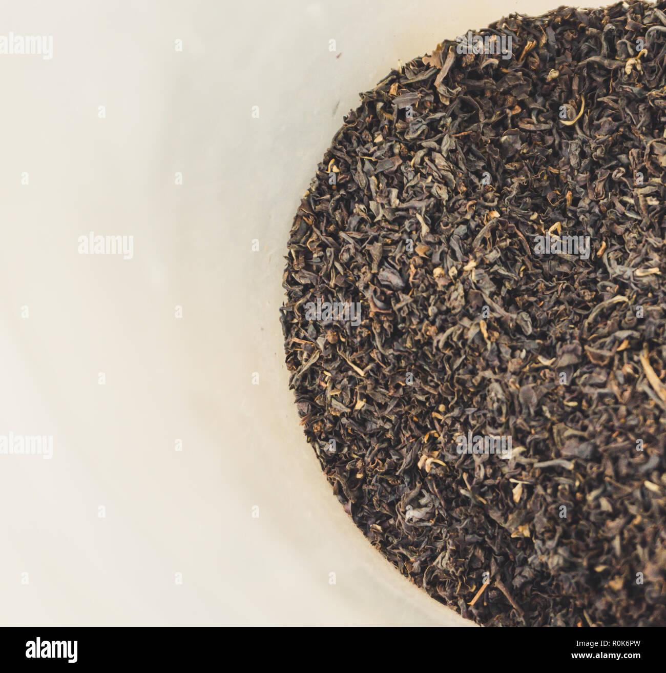 Closeup of loose black tea within a white frosted glass canister ...