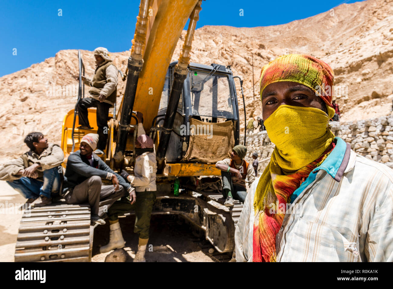 A portrait of a labour in front of an excavator, who lives in Jharkhand ...