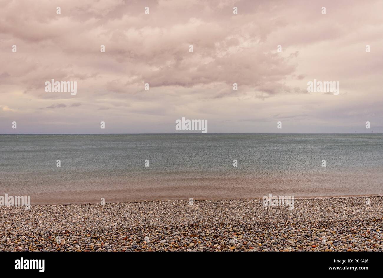 Dawn at the sea front with a pebble beach and dramatic clouds Stock ...
