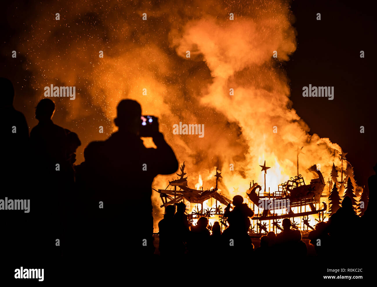 Members of the public view enjoy a bonfire in the shape of a Christmas ...