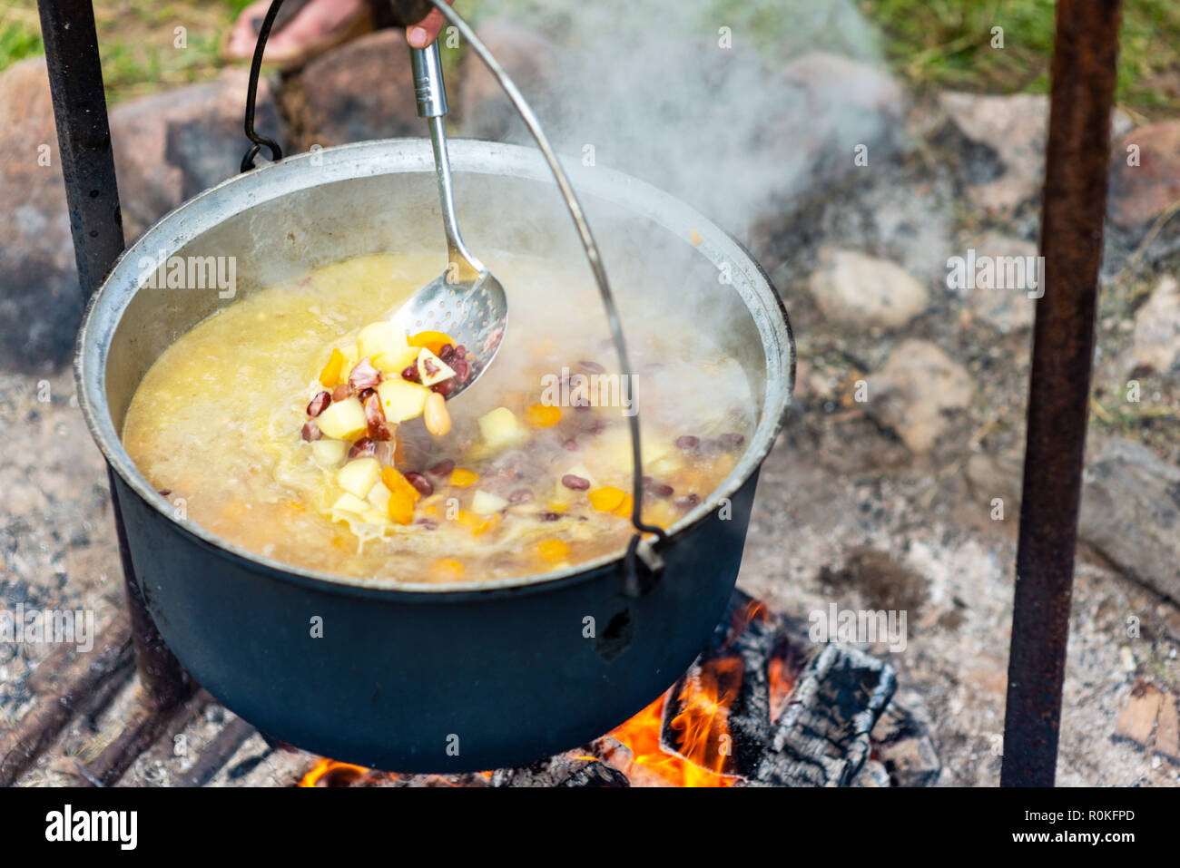 Cooking food in a pot on campfire. Summer camping concept Stock Photo ...