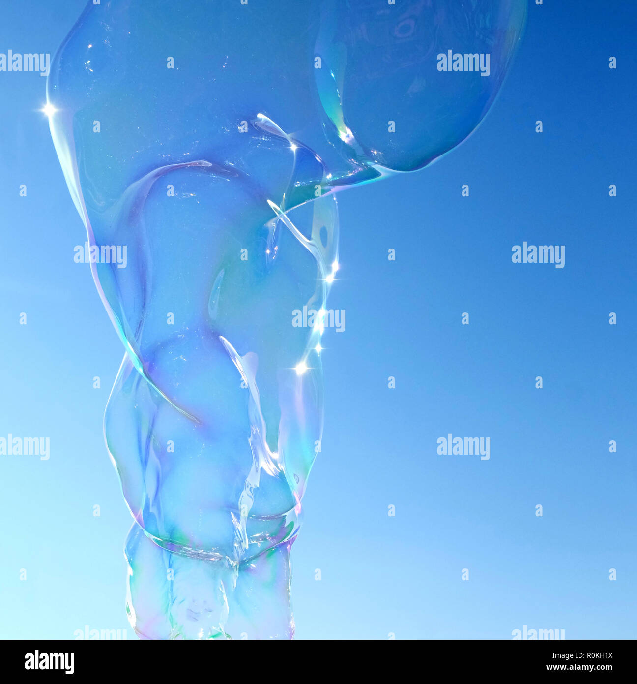 A big bubble floating in the sky, the sky is bright blue behind, the ...