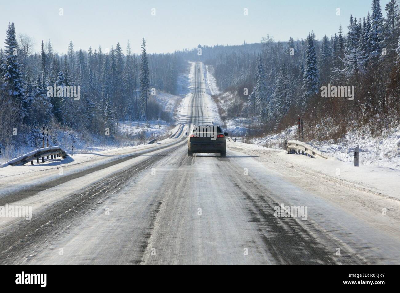 Winter landscape with icy tarmac road on the smooth hills covered with ...