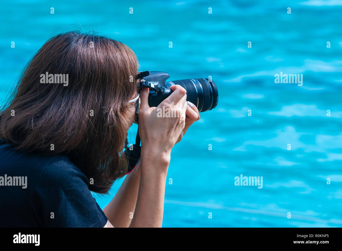 Female photographer taking picture with her DSLR camera at a swimming ...