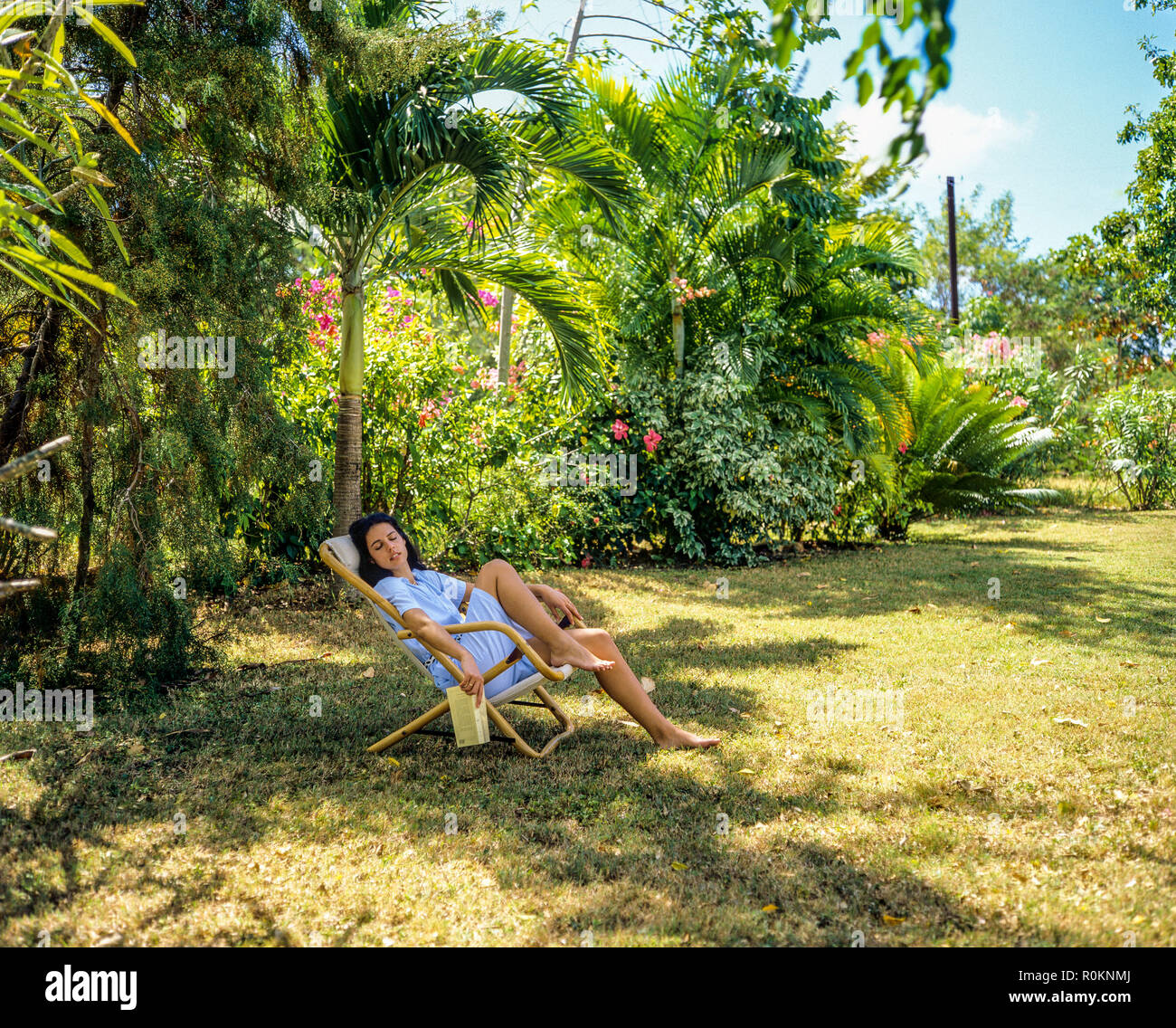 Young woman napping in deck chair, tropical garden, Guadeloupe, French ...