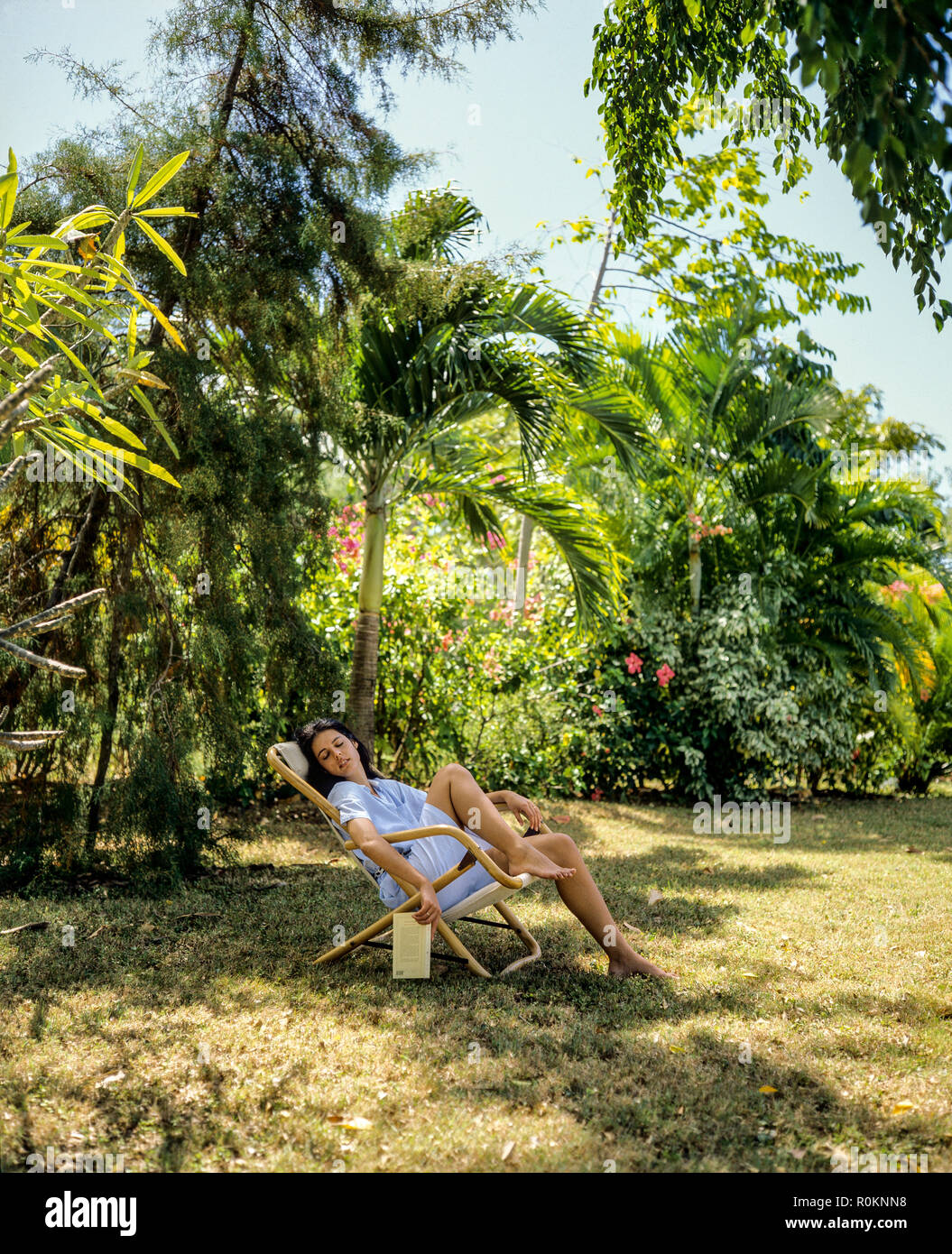 Young woman napping in deck chair, tropical garden, Guadeloupe, French ...