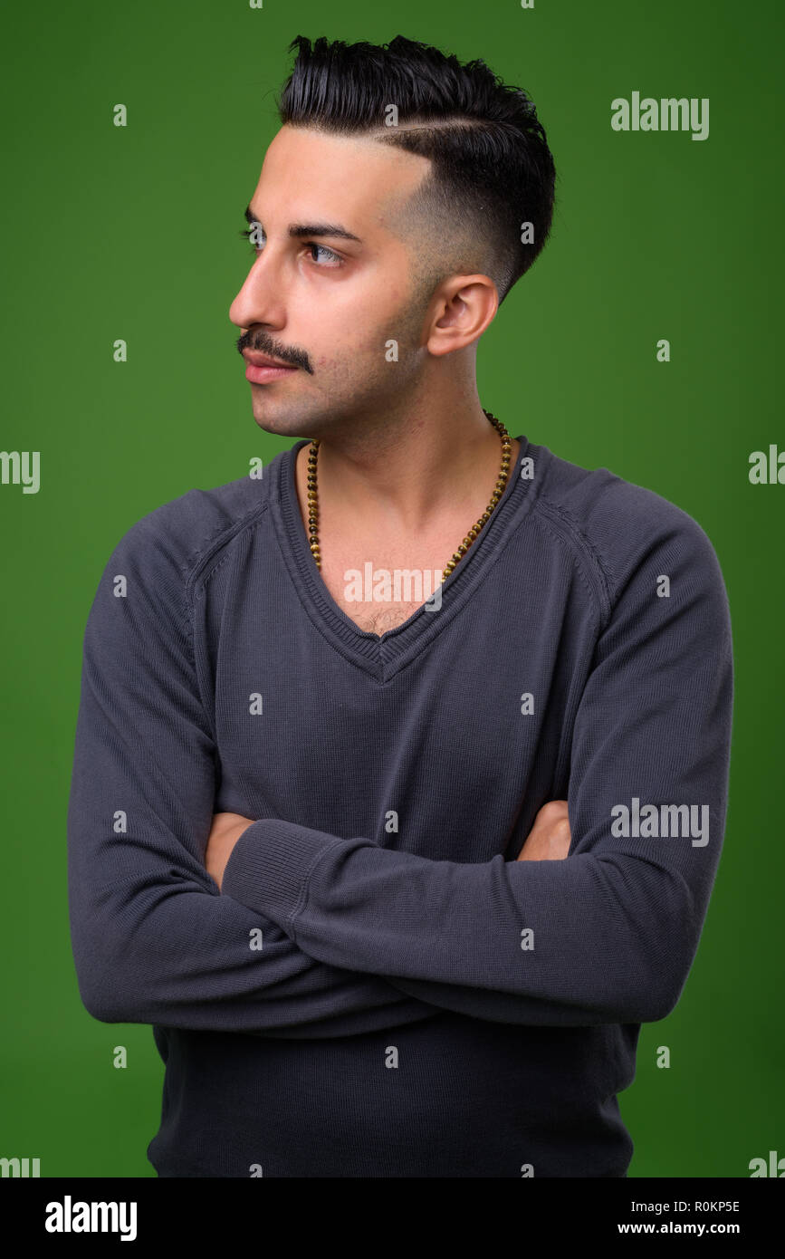 Young handsome Iranian man with mustache against green backgroun Stock ...