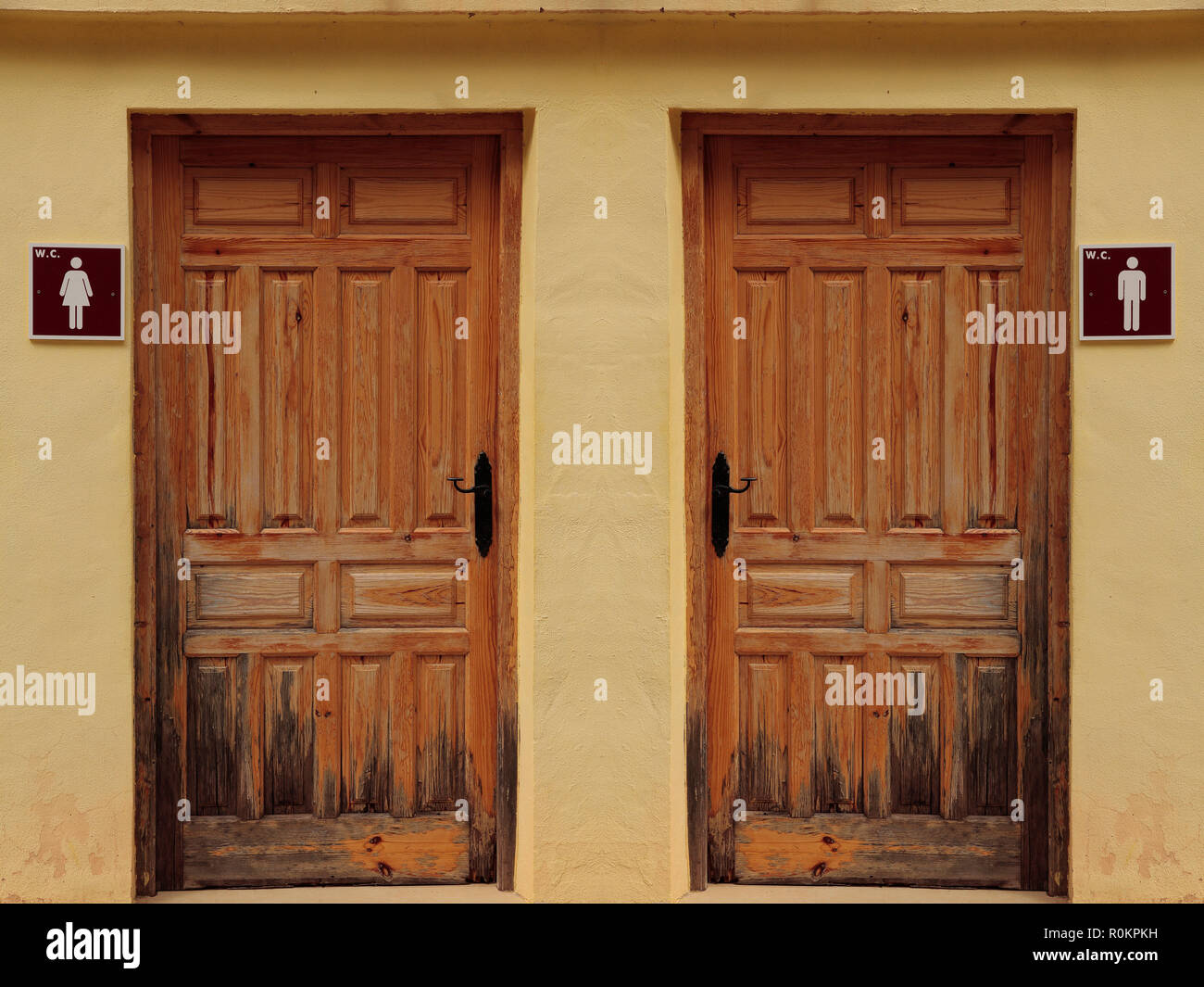 signs and bathroom wooden doors closed on a yellow facade Stock Photo ...