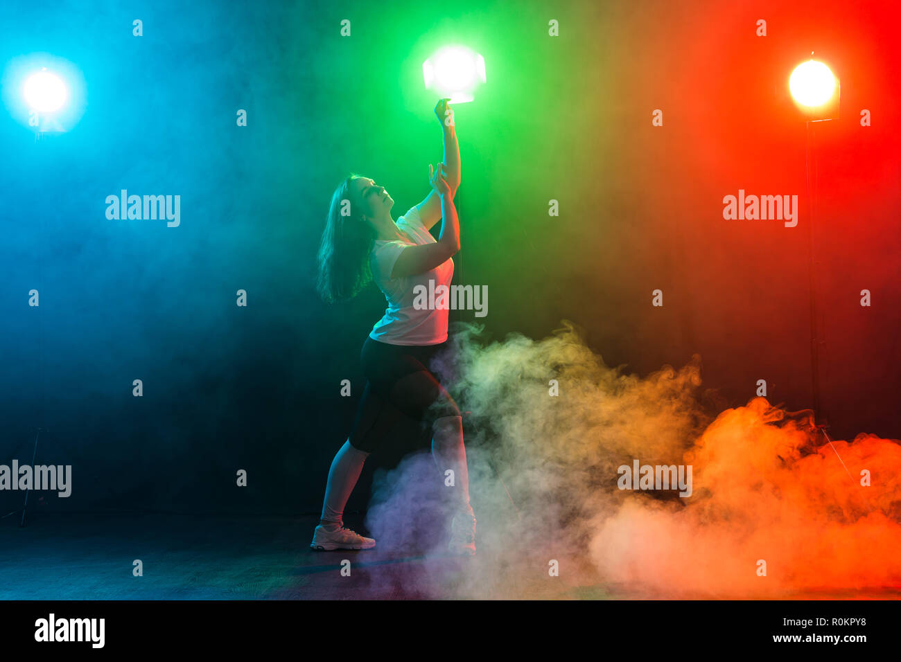 Young beautiful slim woman dancing jazz-funk on colourful background ...