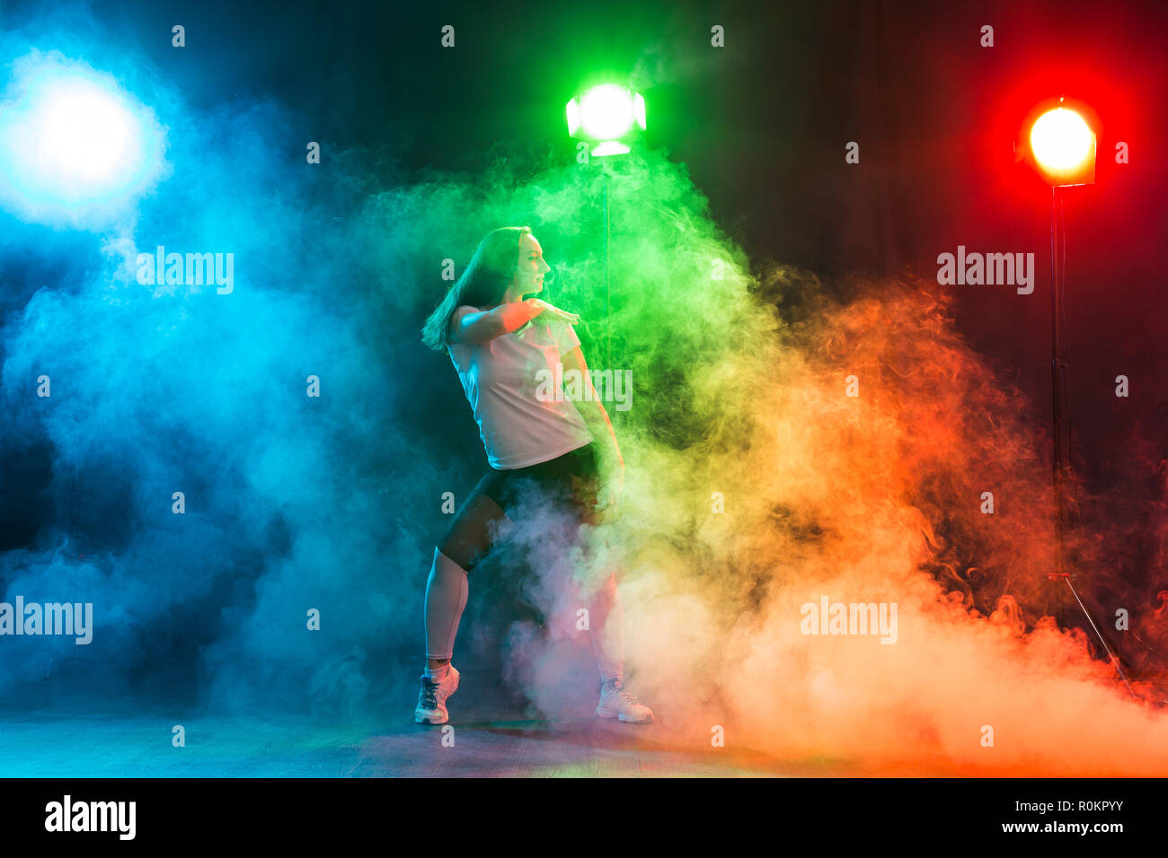 Modern dance concept - Cheerleading young woman dancing on coloured ...