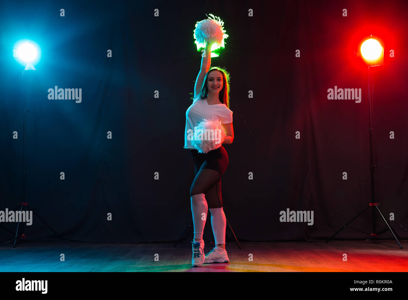 Cheerleading young woman dancing with pom-poms on colourful background ...