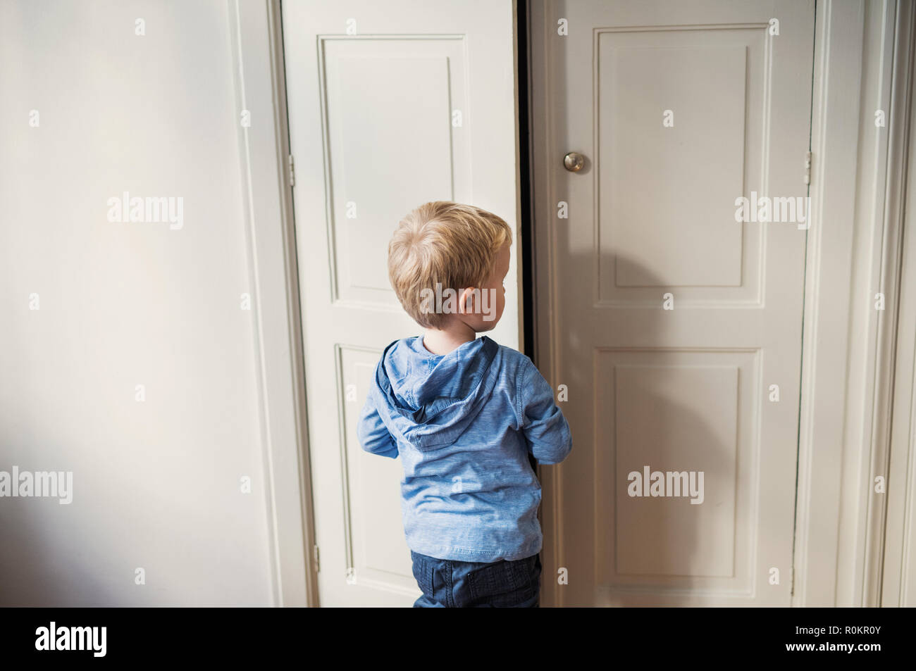 A rear view of toddler boy standing near door inside in a bedroom Stock ...