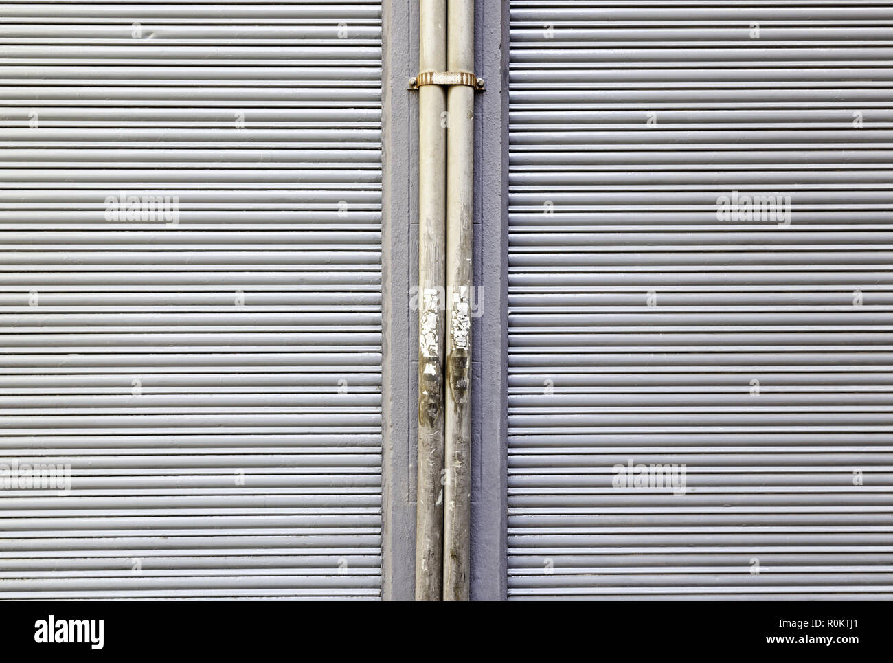 Pipes in the street, detail of a wall with metal door closed ...