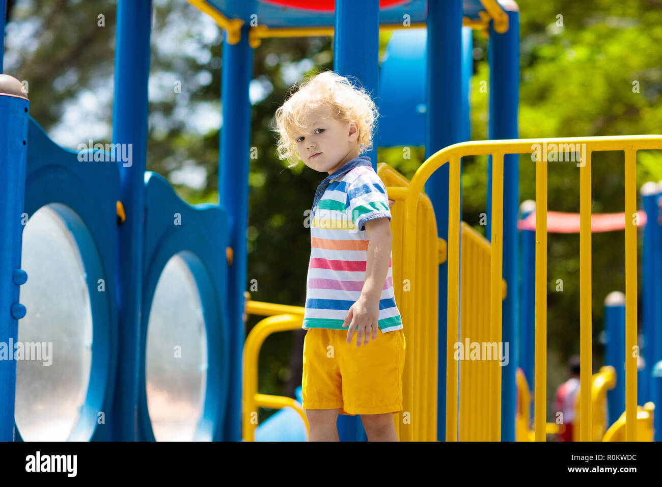 Kids climbing and sliding on outdoor playground. Children play in sunny ...