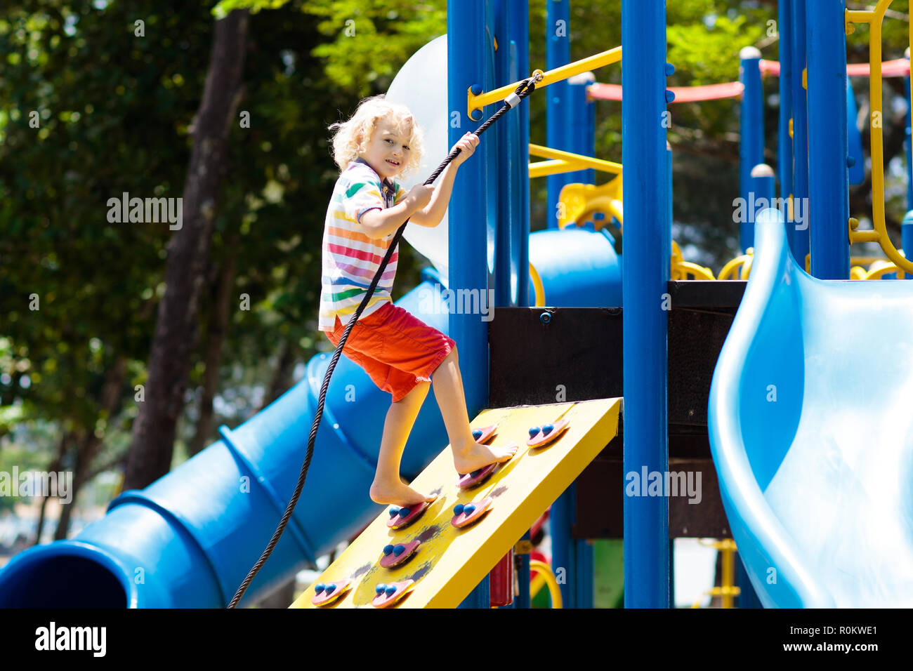 Kids climbing and sliding on outdoor playground. Children play in sunny ...