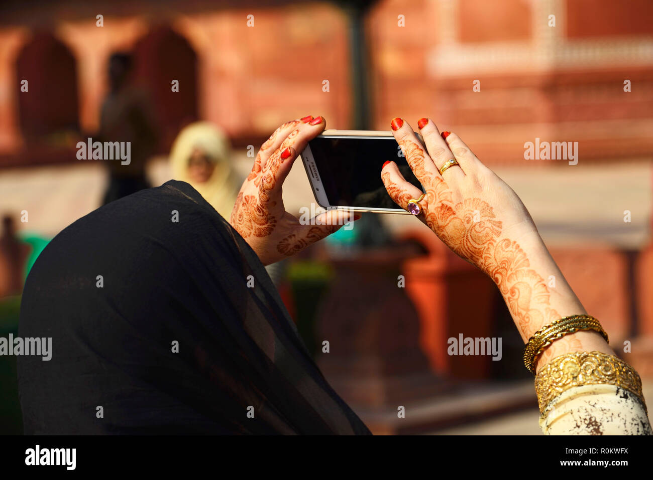 Muslim woman with Henna-decorated hands photographing with smartphone ...