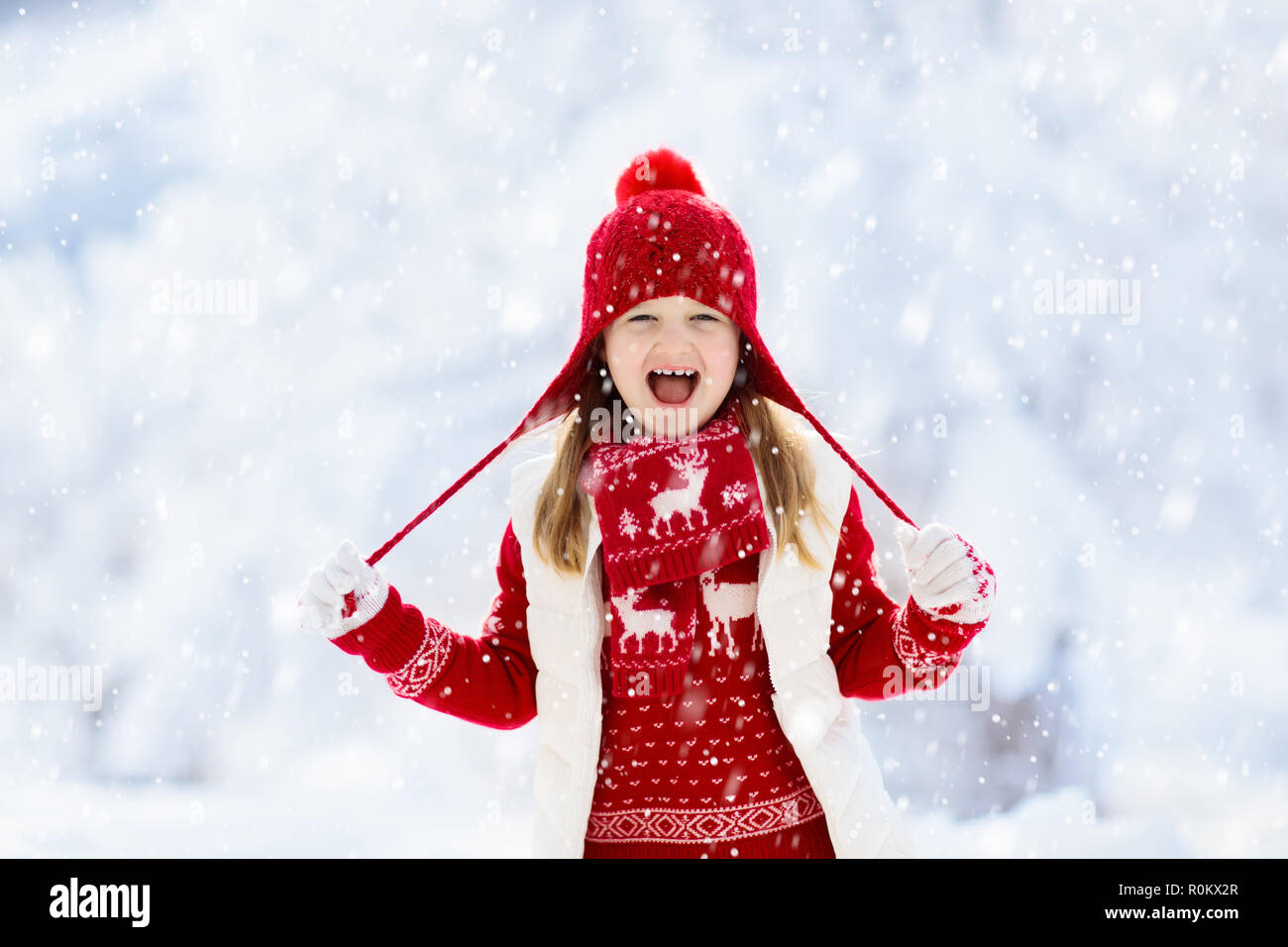 Child in red hat playing in snow on Christmas vacation. Winter outdoor ...